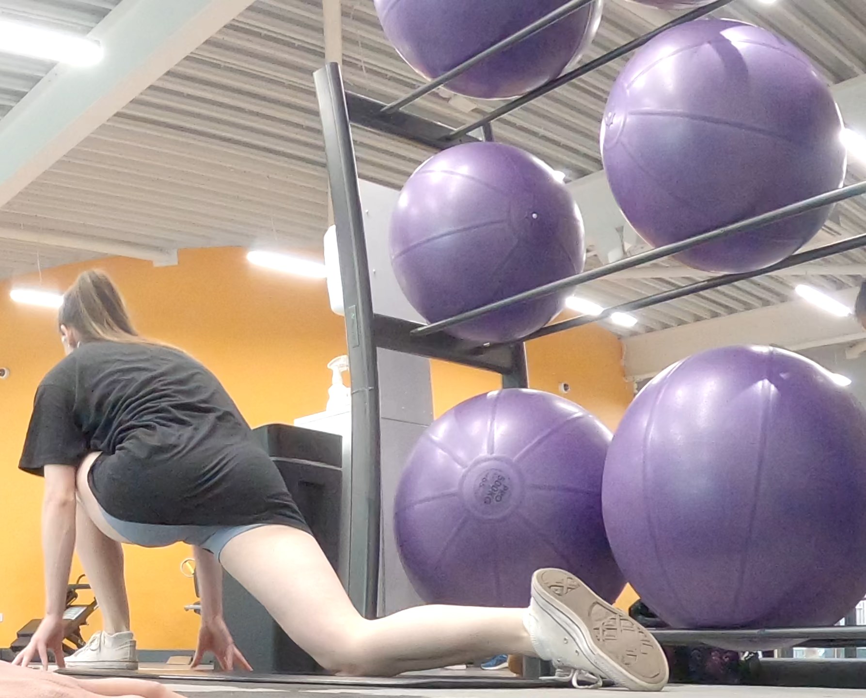 Flexible Gym Cutie Wearing Grey Shorts Stretching Out On The Mats